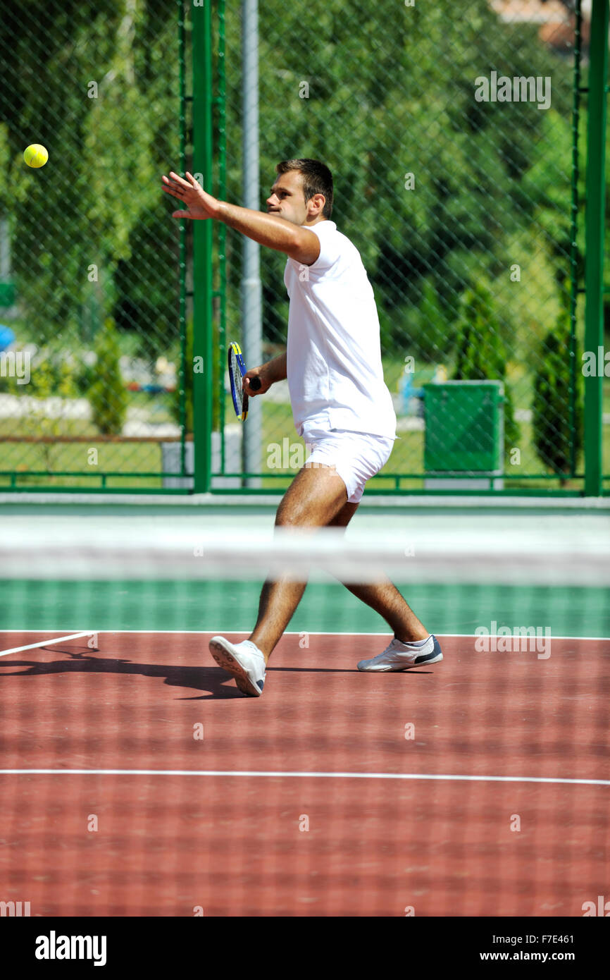 young man play tennis outdoor on orange tennis court at early morning ...