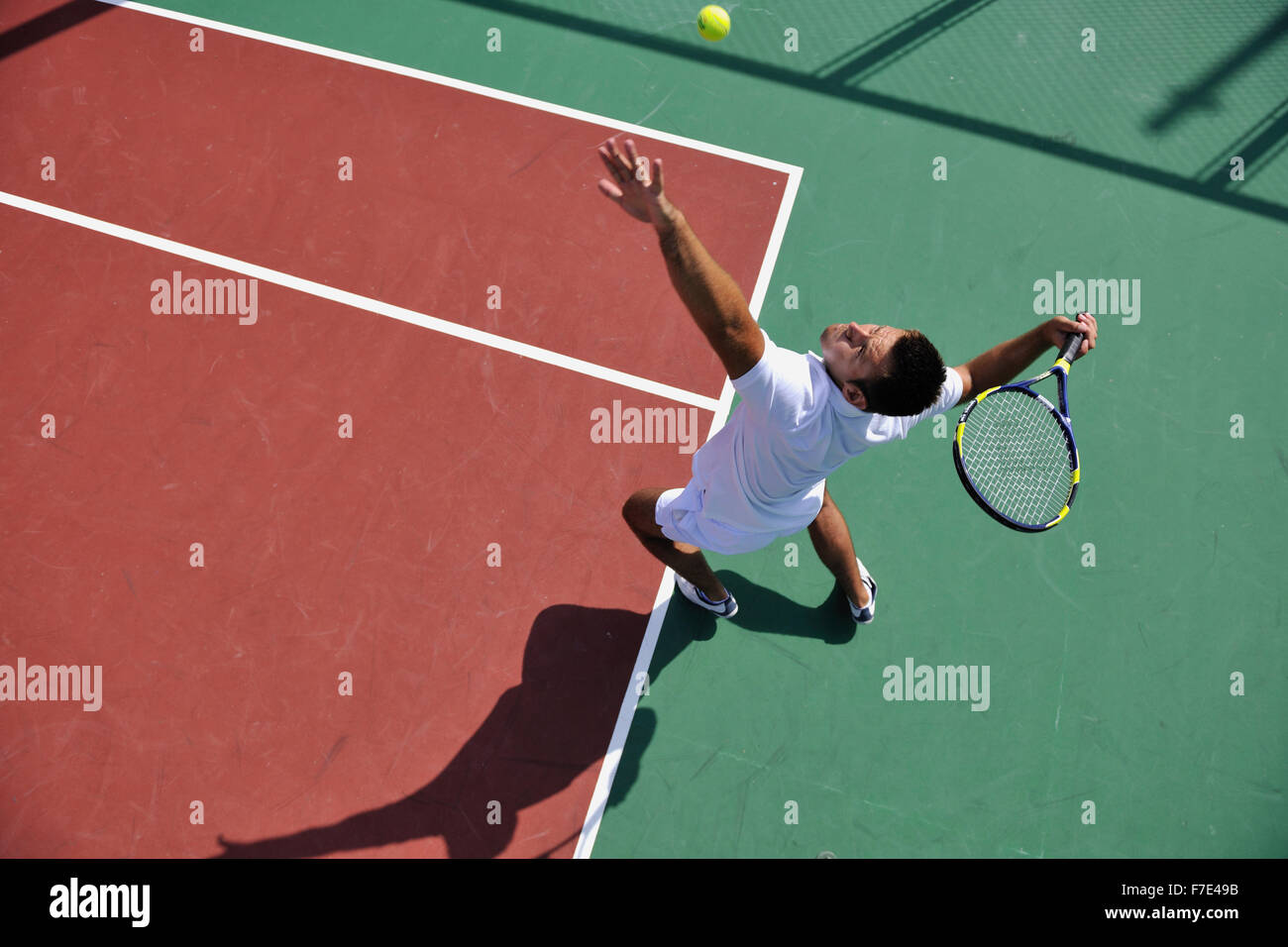 young man play tennis outdoor on orange tennis court at early morning ...