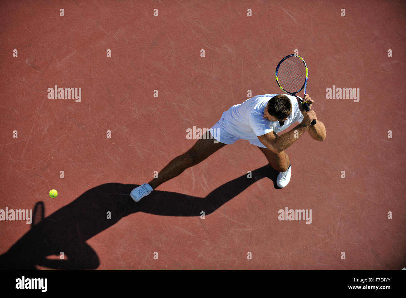 young man play tennis outdoor on orange tennis court at early morning ...