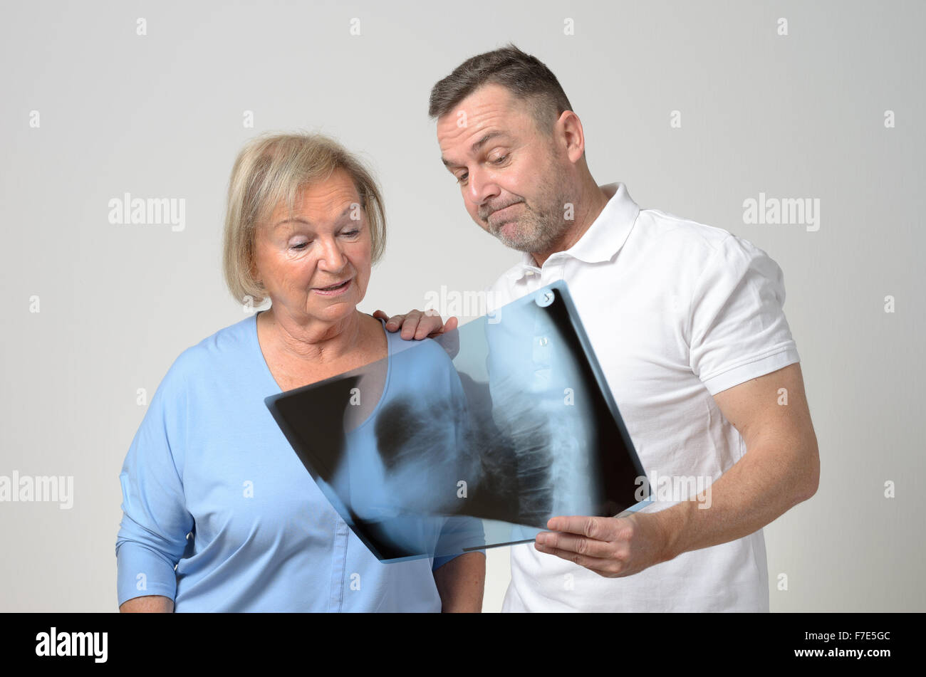 Doctor discussing an x-ray with an elderly female patient as they stand ...