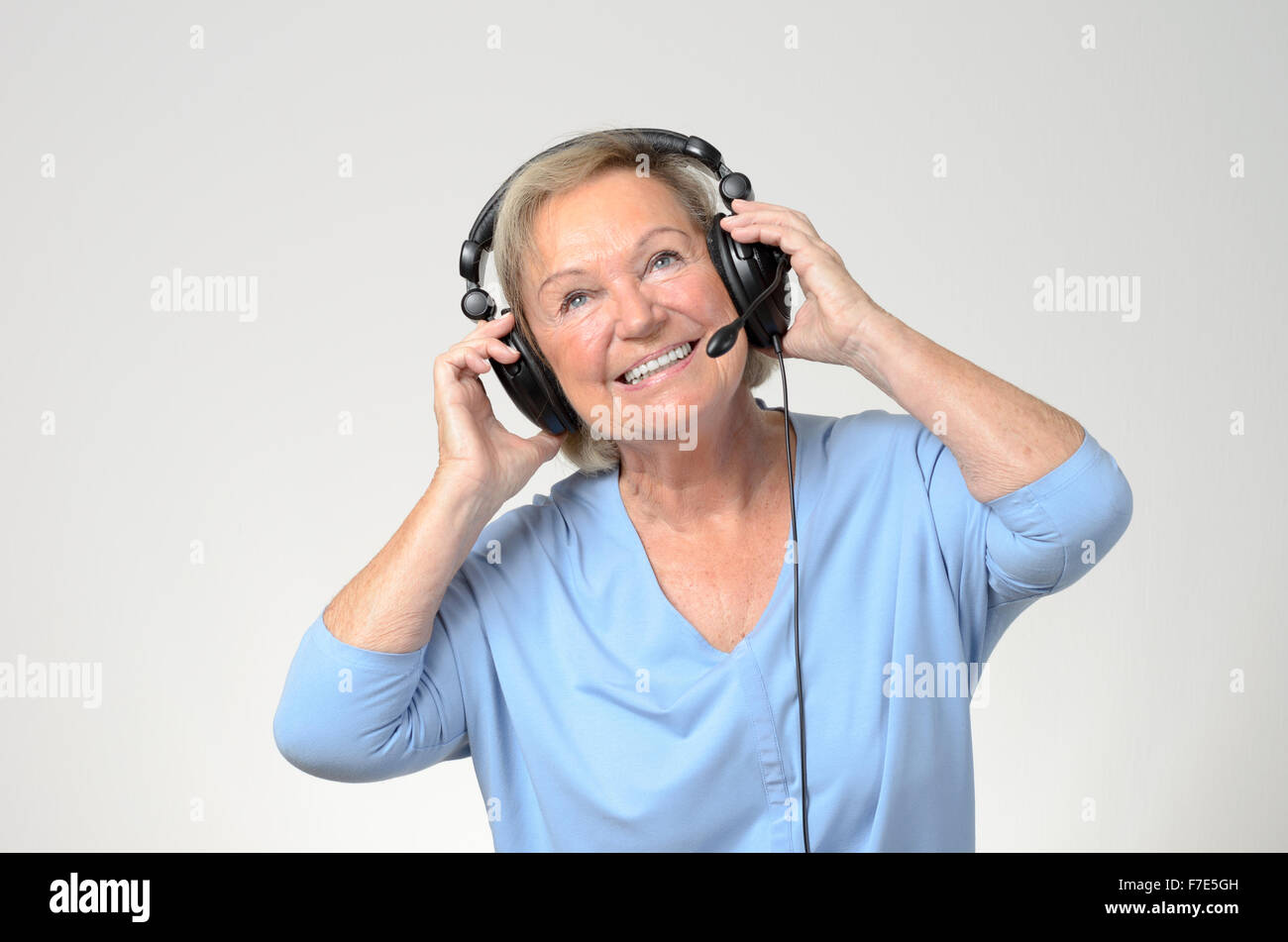 Excited senior woman listening to music on a set of stereo headphones ...
