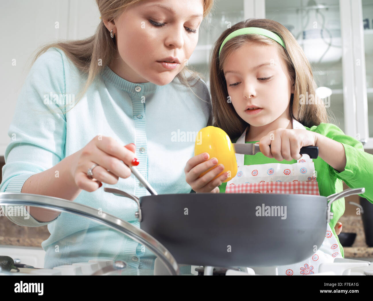 view of young beautiful girl cooking at the kitchen with her mama Stock ...