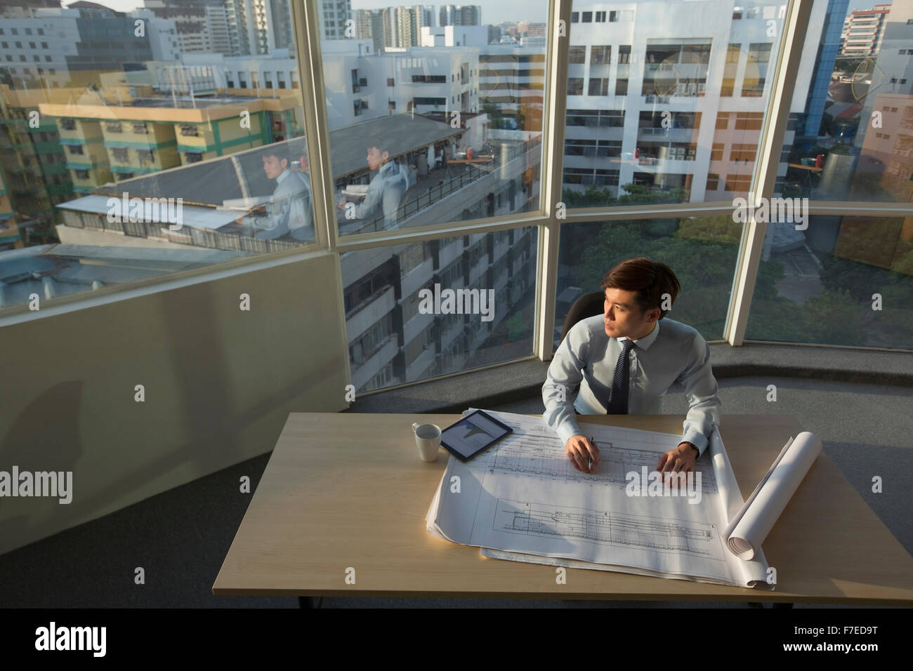 Singapore, Architect sitting in office looking out of window Stock ...