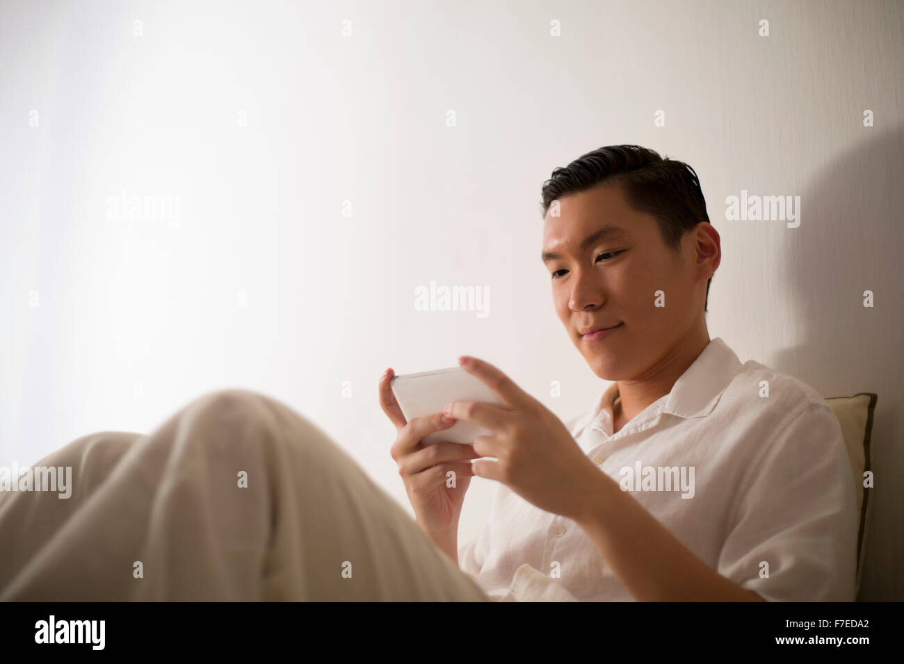 Singapore, Young man texting on sofa Stock Photo - Alamy