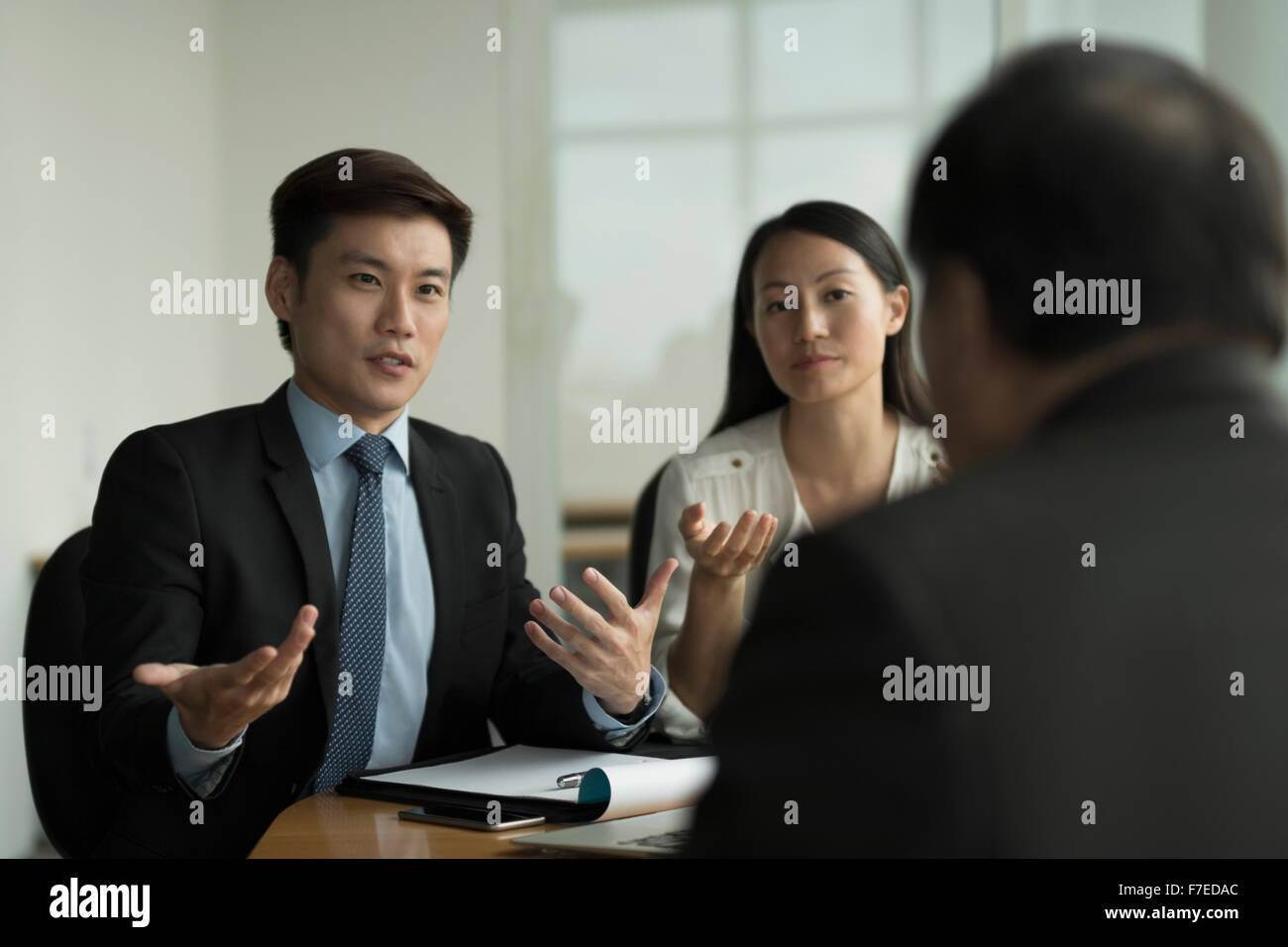 Singapore, Three business people talking at desk Stock Photo - Alamy