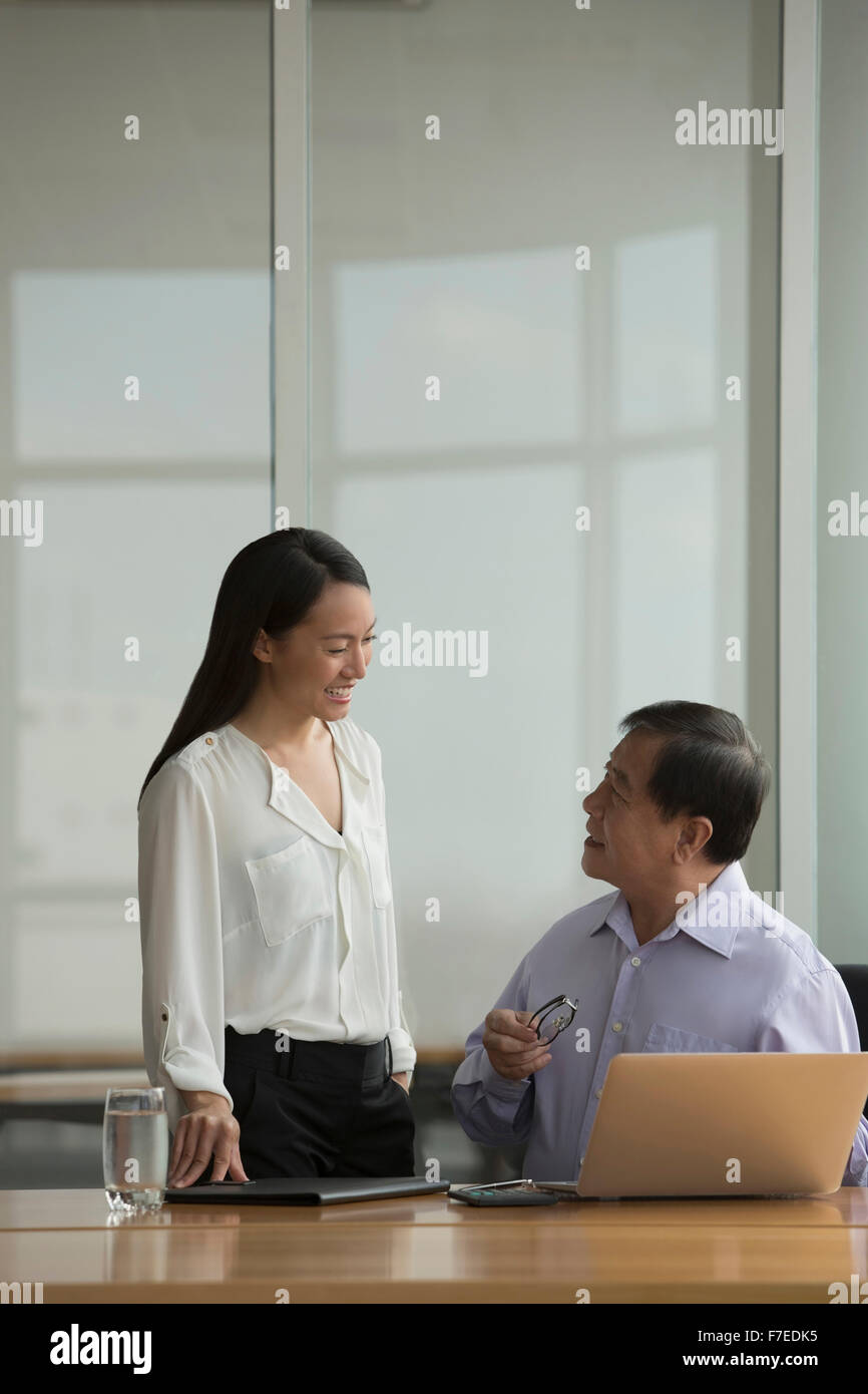 Singapore, Two business people talking at desk in office Stock Photo ...