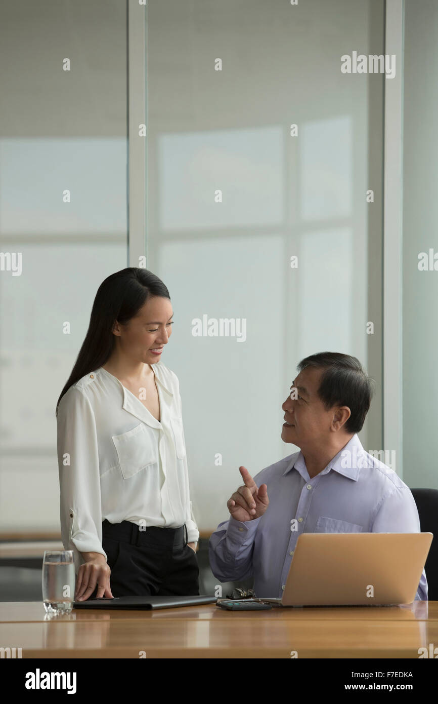 Singapore, Two business people talking at desk in office Stock Photo ...
