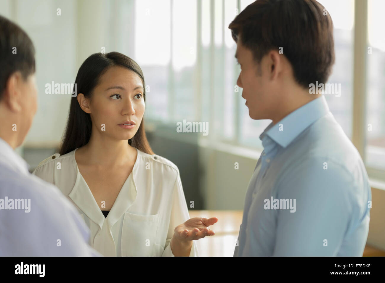 Singapore, Three people talking in office Stock Photo - Alamy
