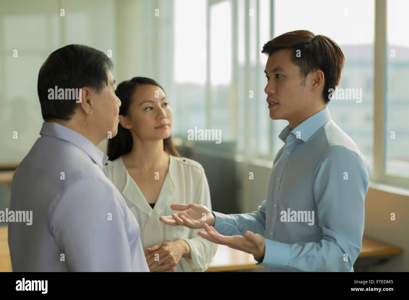 Singapore, Three people talking in office Stock Photo - Alamy