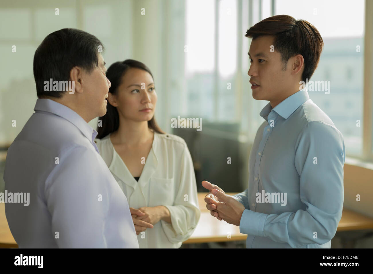 Singapore, Three people talking in office Stock Photo - Alamy