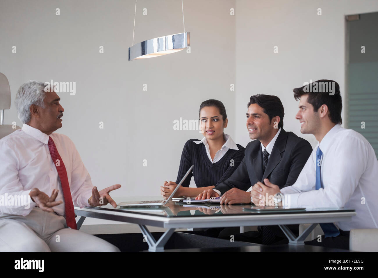 India, Senior businessman leading discussion with three young ...