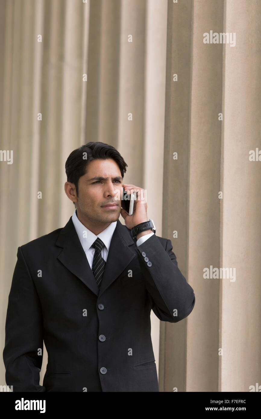 Man in suit using mobile phone in front of columns Stock Photo - Alamy