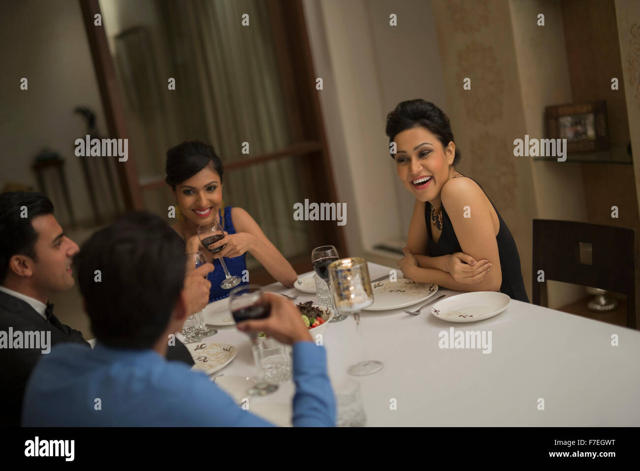 Four friends at formal dinner laughing Stock Photo - Alamy