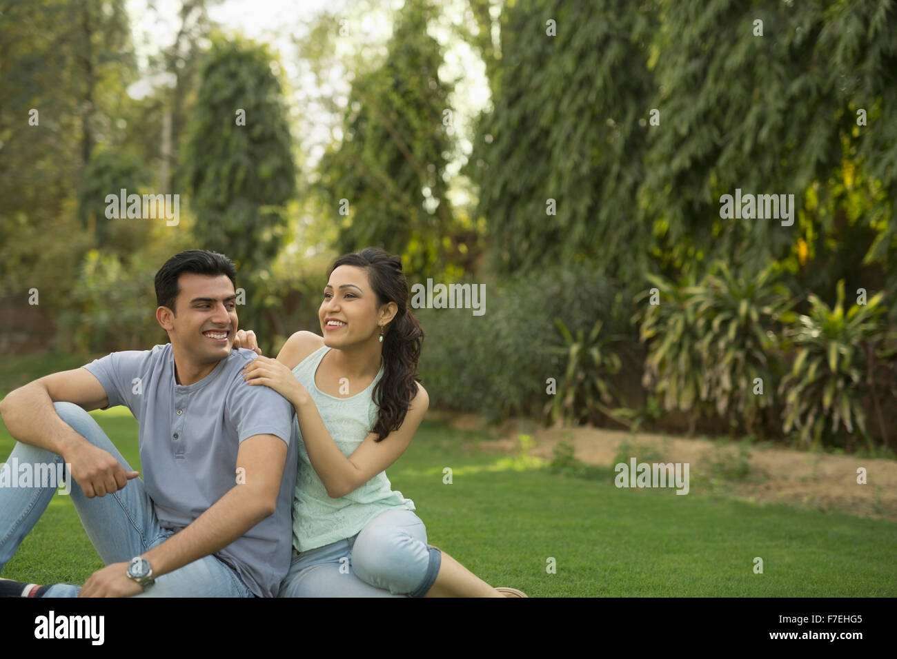 Woman sitting behind man on grass Stock Photo - Alamy