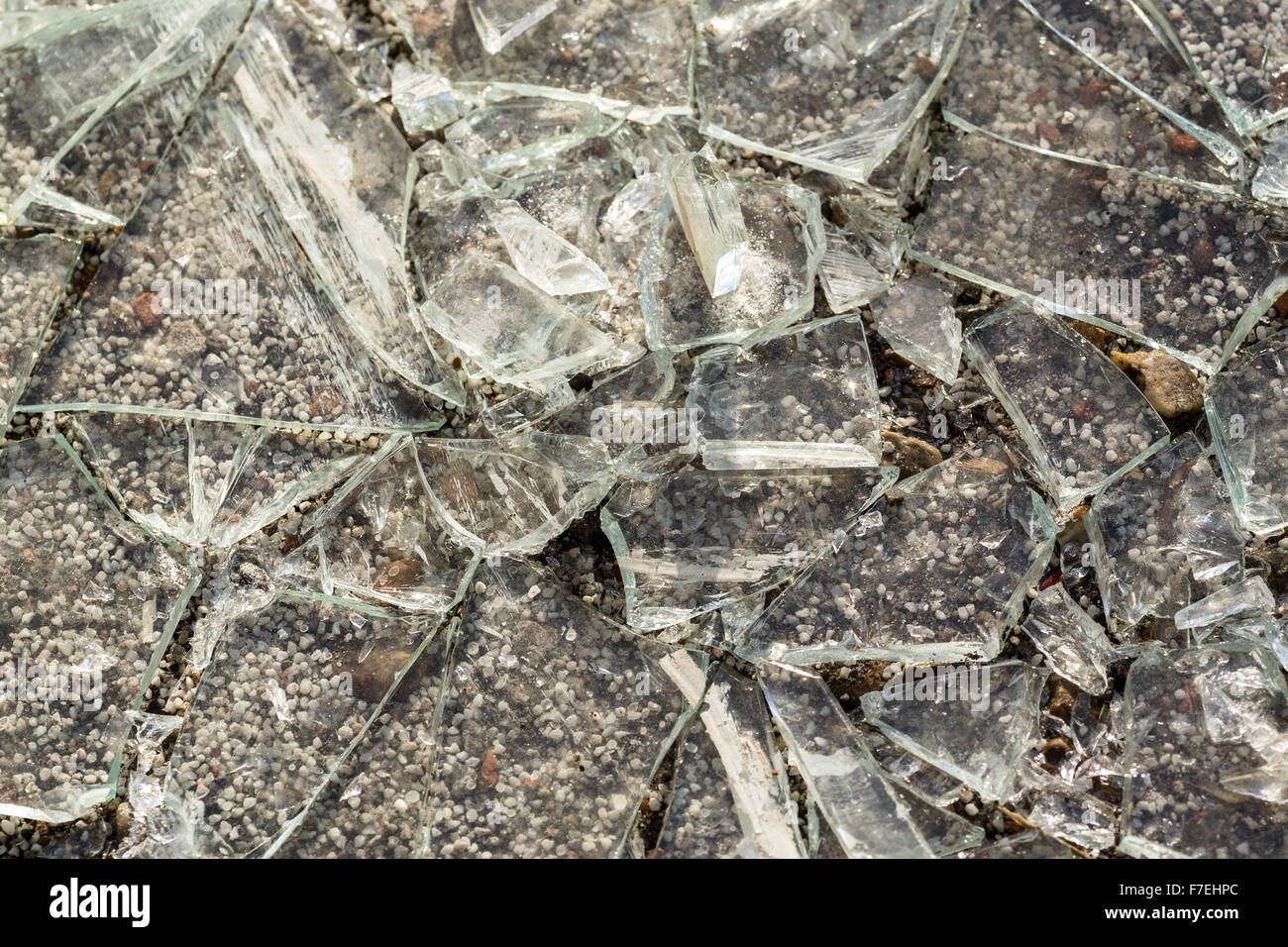 Macro shot of broken glass shards on a concrete pavement background ...