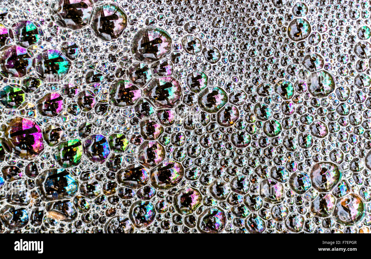 Multicolored soap foam bubbles on the surface of a puddle of water ...