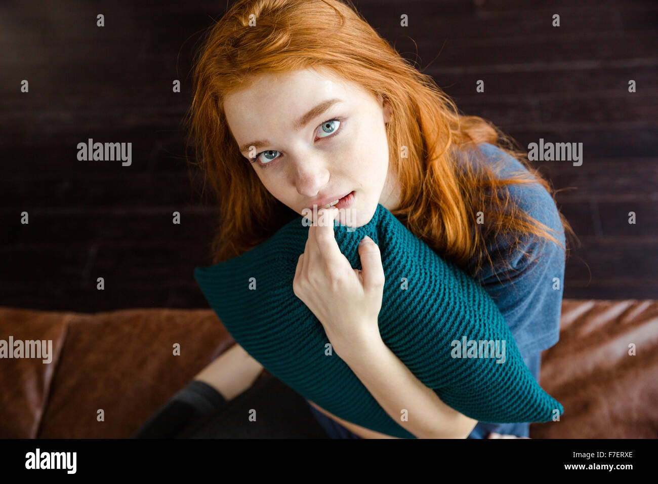 Top View Of Lovely Cute Curious Redhead Young Lady Sitting On Brown Leather Sofa Hugging