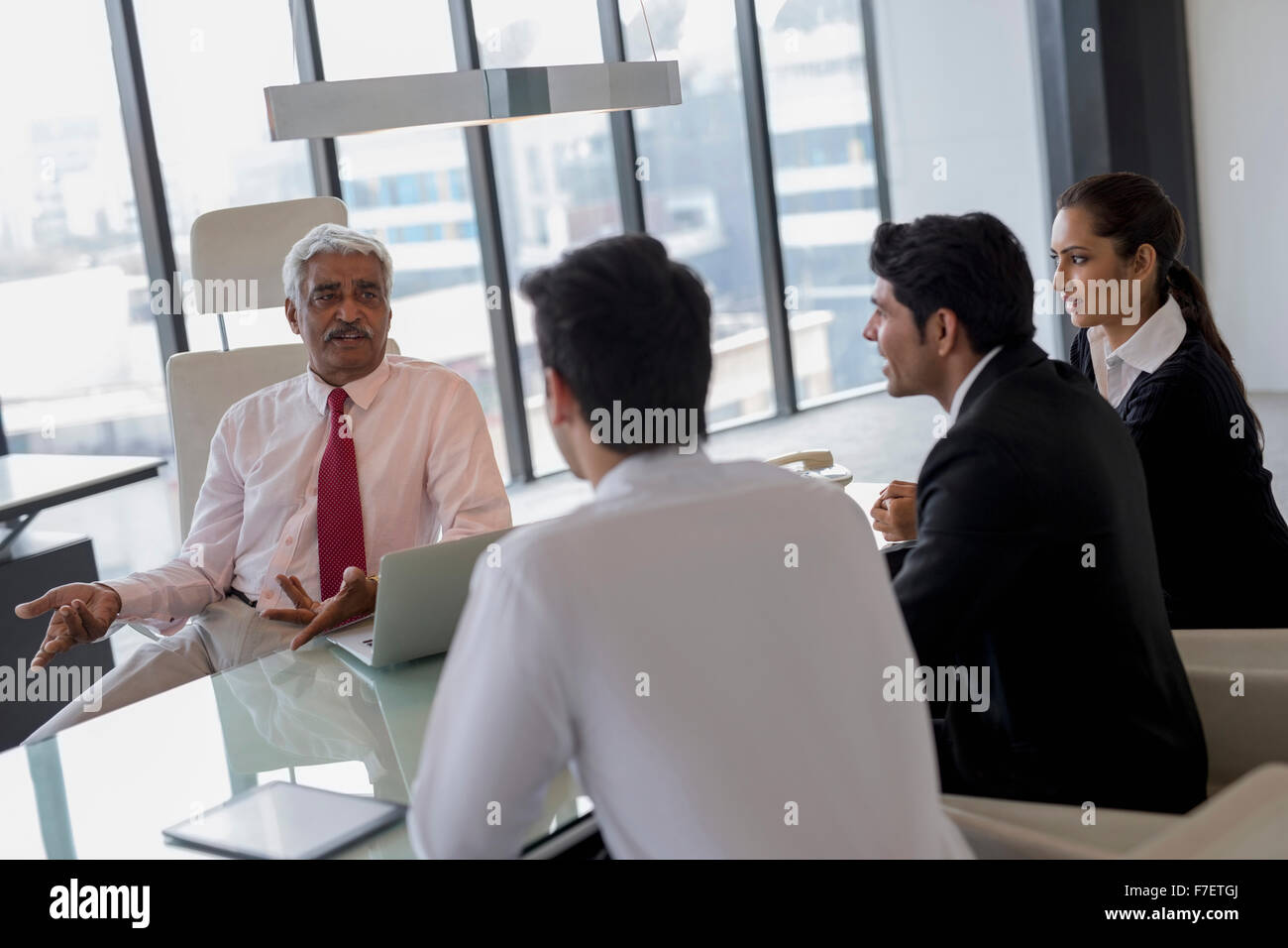 India, Senior businessman leading discussion with three colleagues ...
