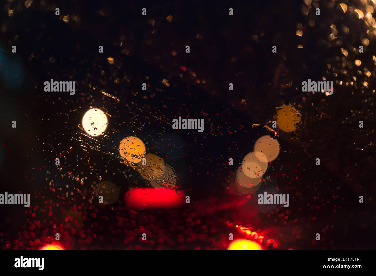 Defocused car lights in a city center with rainwater reflections on the ...