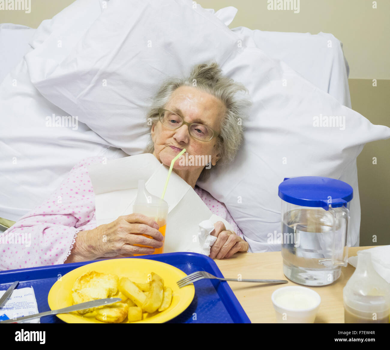 Ninety year old female patient in NHS hospital drinking from straw with ...