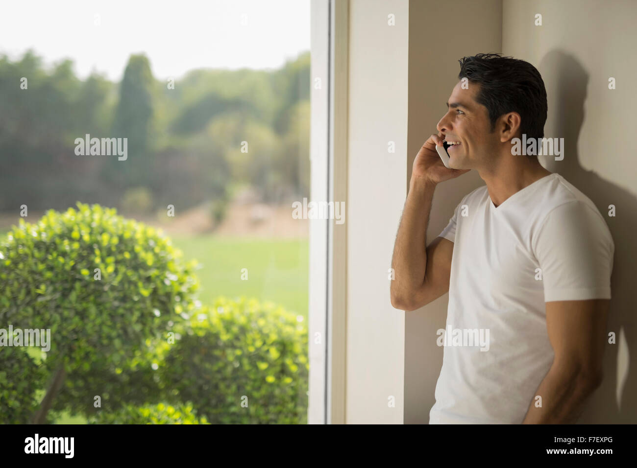 India, Man talking on mobile phone and looking through window Stock ...