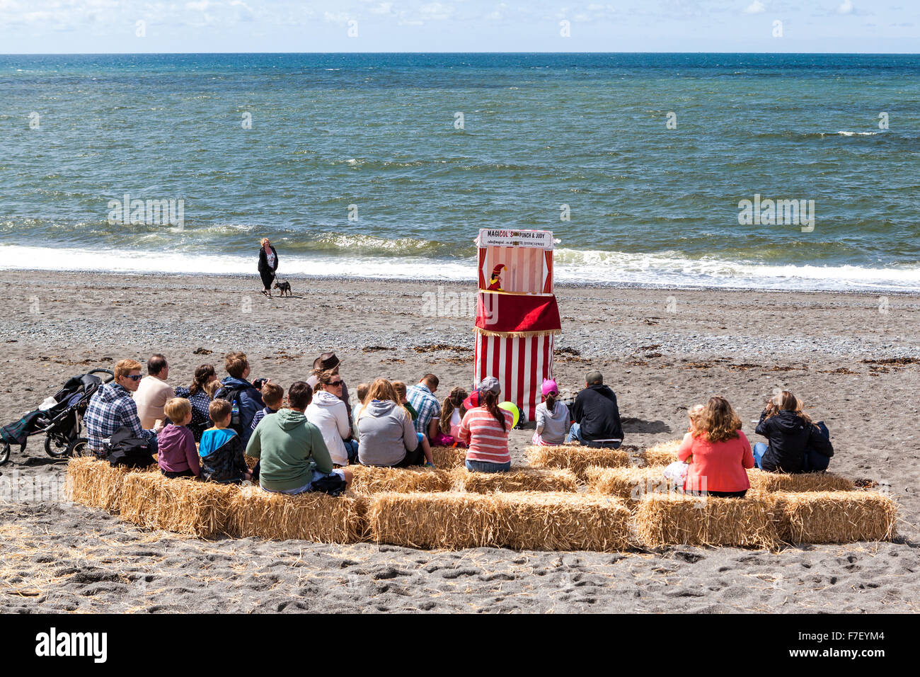 people sitting on hay bales watching a punch and judy show on the beach ...
