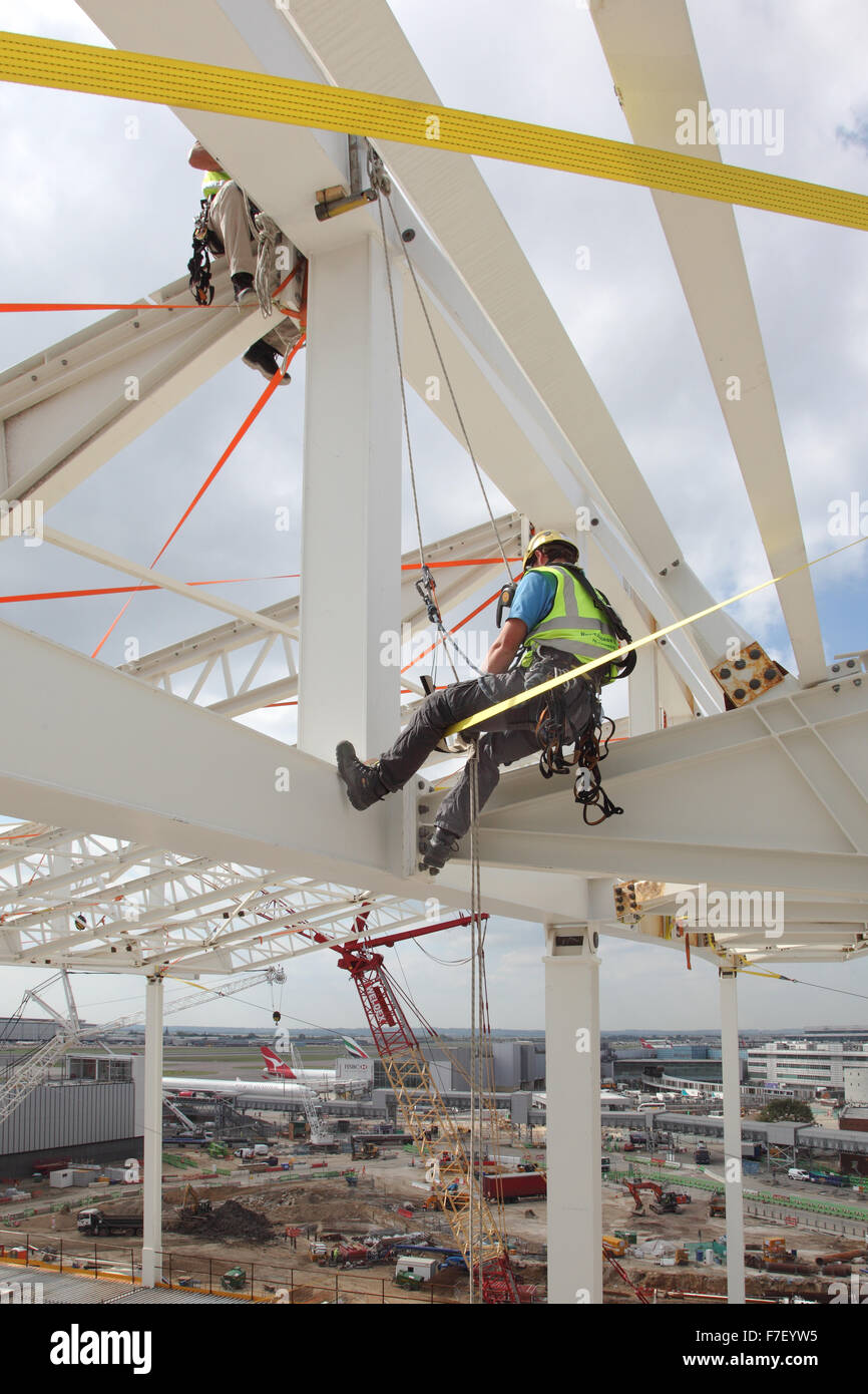 Construction workers use ropes to access roof steelwork for the ...