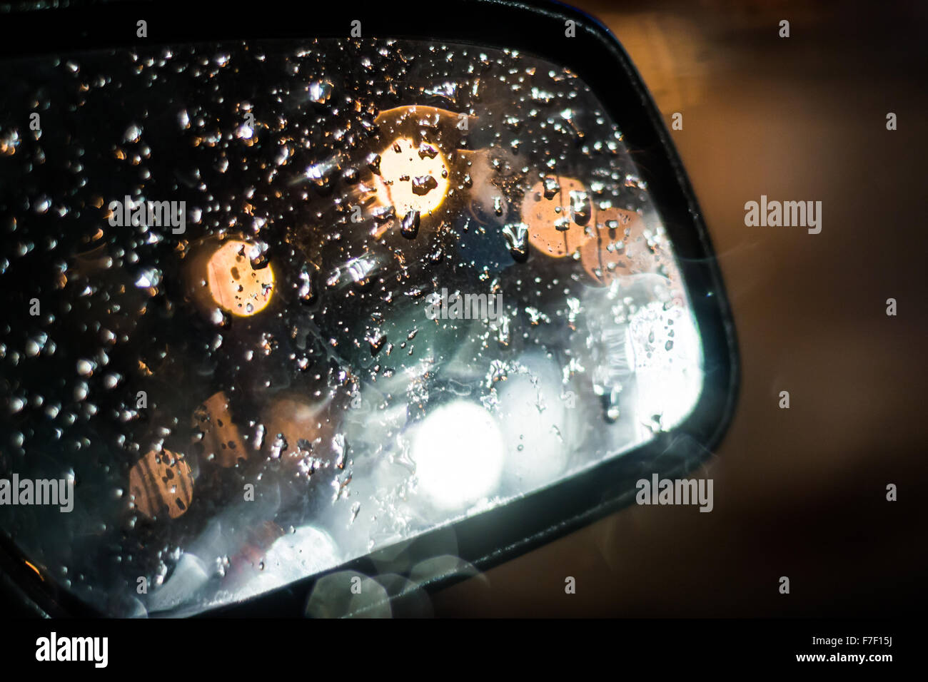 Car wing mirror reflects headlights and streetlight creating a ...