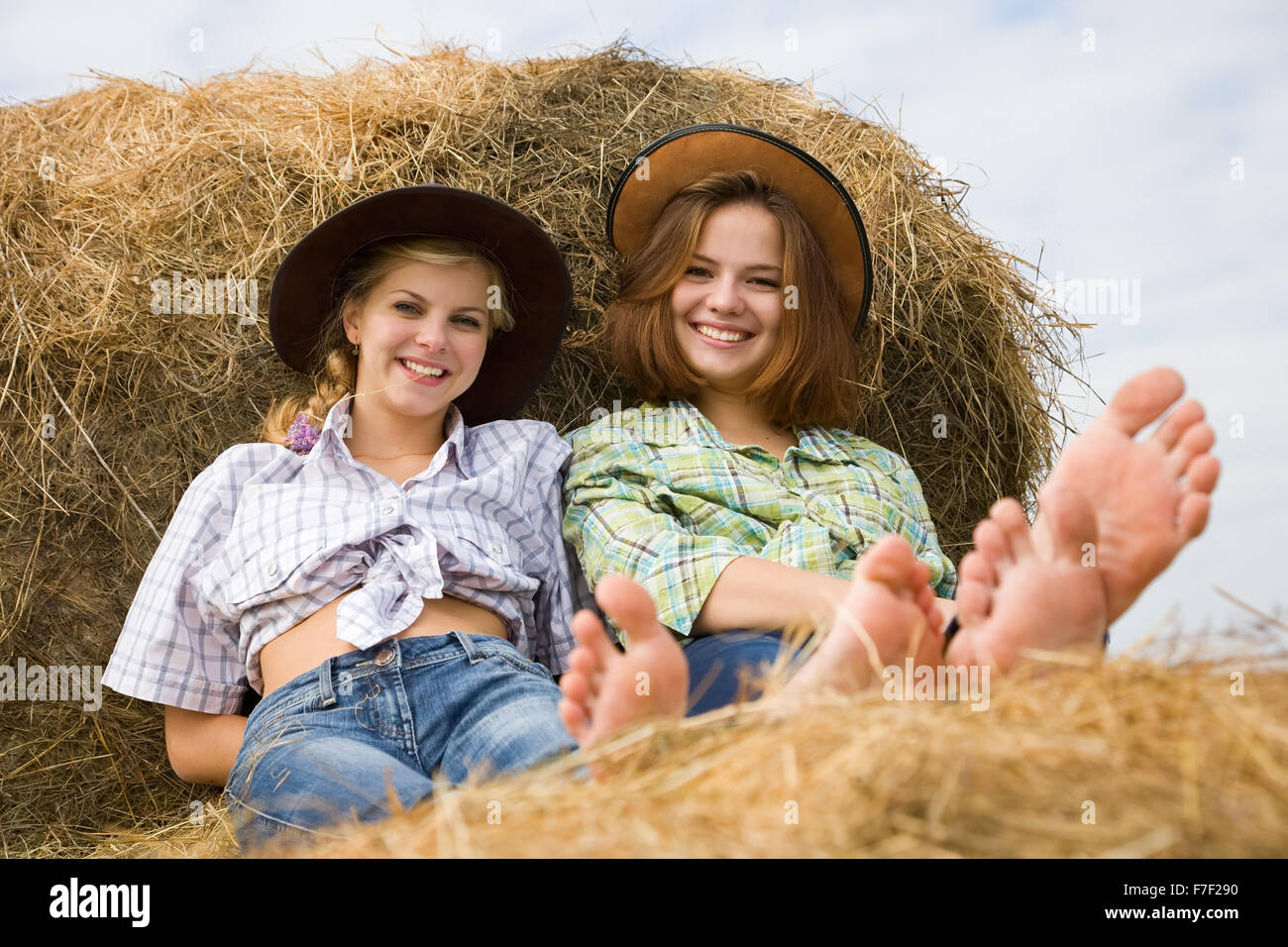 country girls restings on fresh hay bale Stock Photo - Alamy