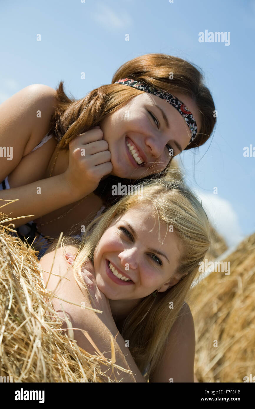 Happy girls on fresh hay at field Stock Photo - Alamy