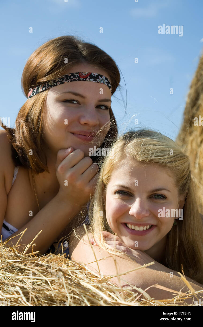 Happy girls on fresh hay at field Stock Photo - Alamy