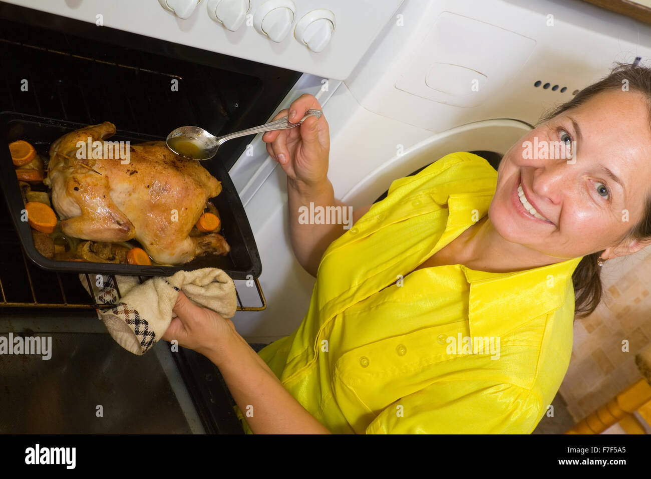 Mature woman cooking chicken on pan in oven Stock Photo - Alamy
