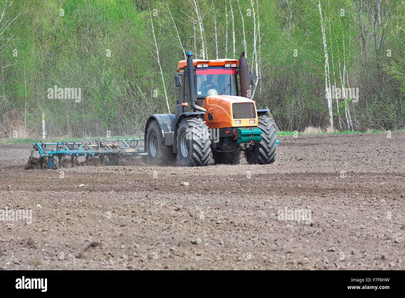 Tractor cultivating the land to prepare the soil for seeding plants ...