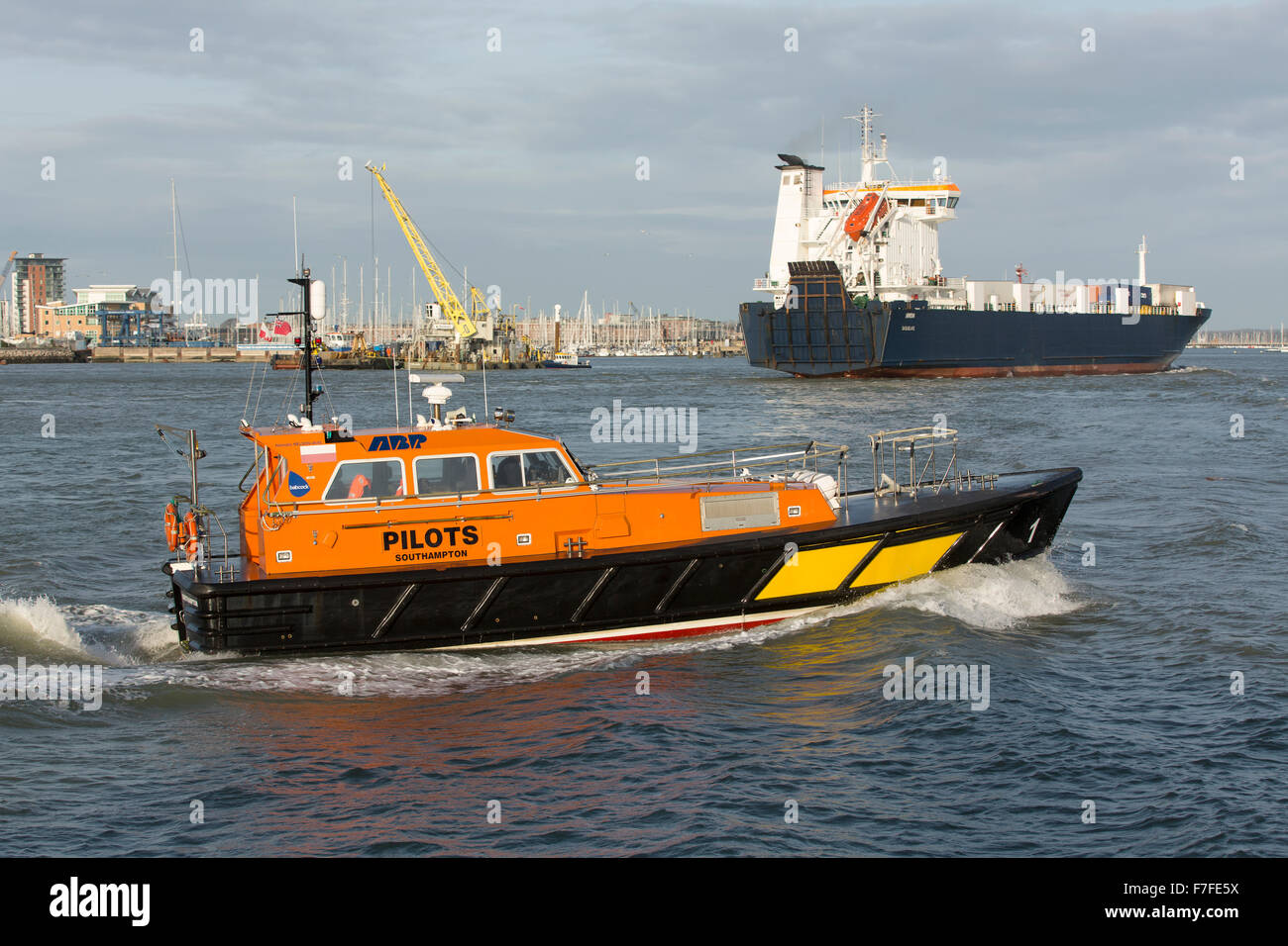 Orange and Black pilot boat crossing Portsmouth harbour at speed with a ...
