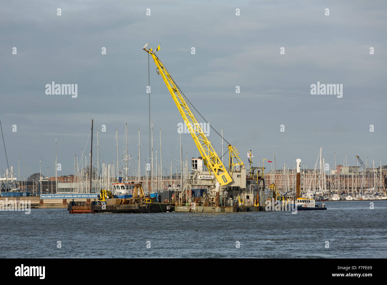 Crane on a floating pontoon in Portsmouth harbour. Performing dredging ...