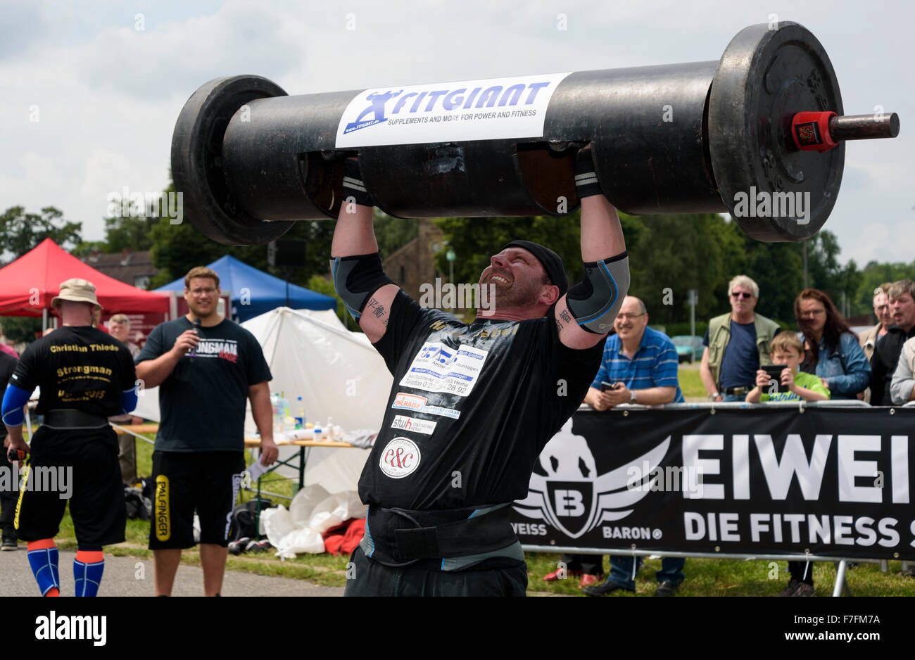 A strong man proves his strength at a public athletics sports event ...