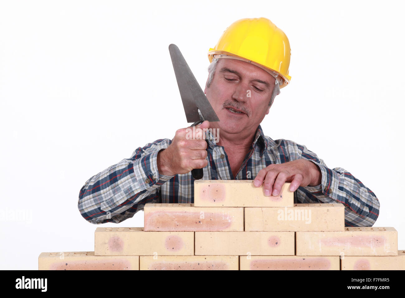 Mason tapping brick into place Stock Photo - Alamy