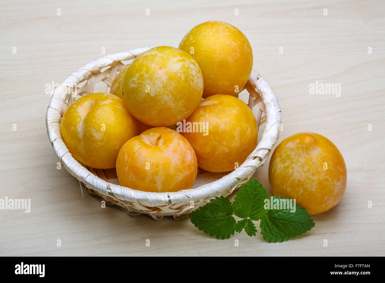 Yellow plums in the basket on wood Stock Photo - Alamy