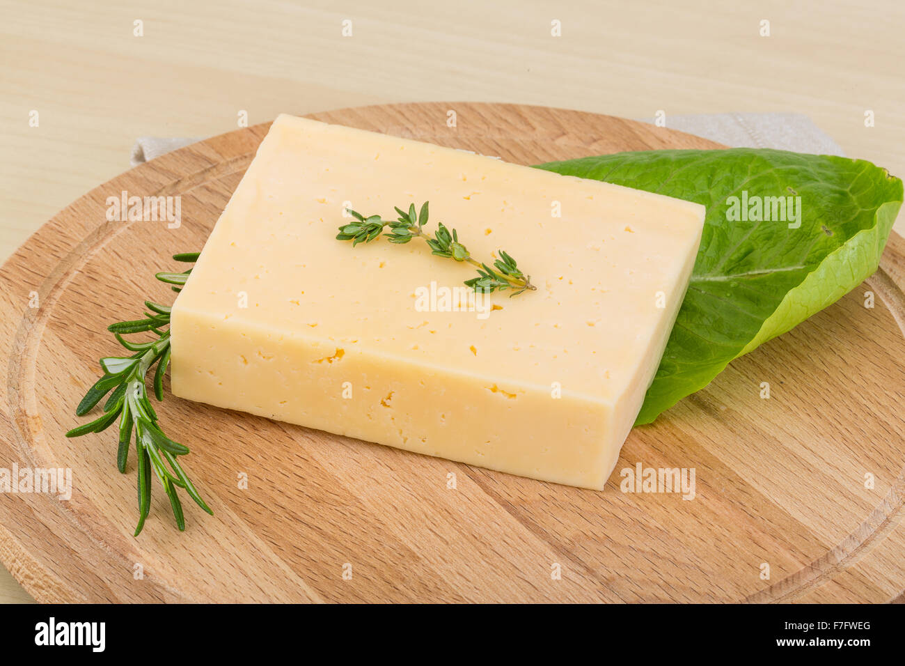 Yellow cheese brick with rosemary and thyme Stock Photo - Alamy