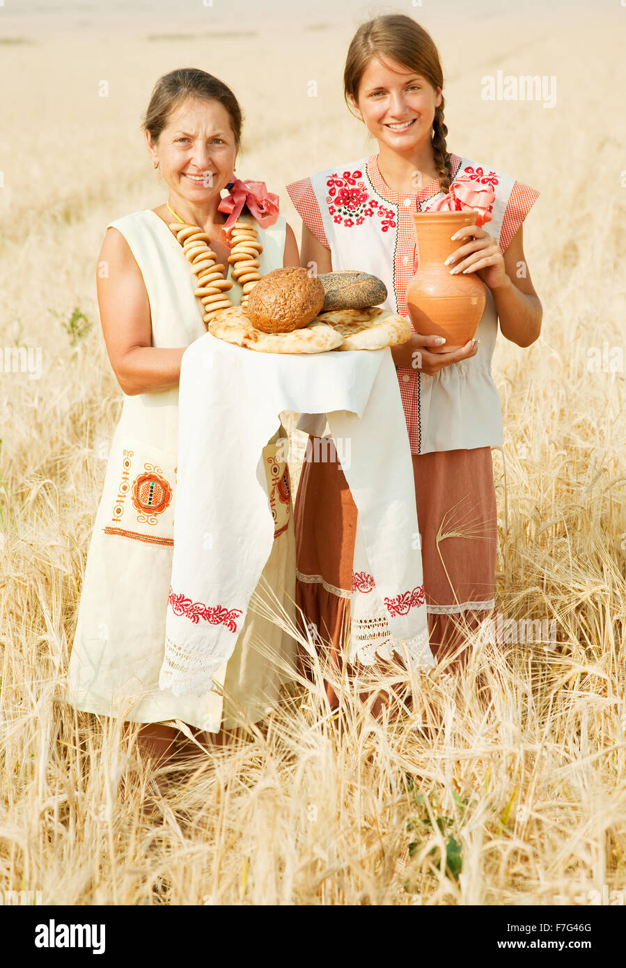 Women in traditional clothes with bread at cereals field Stock Photo ...