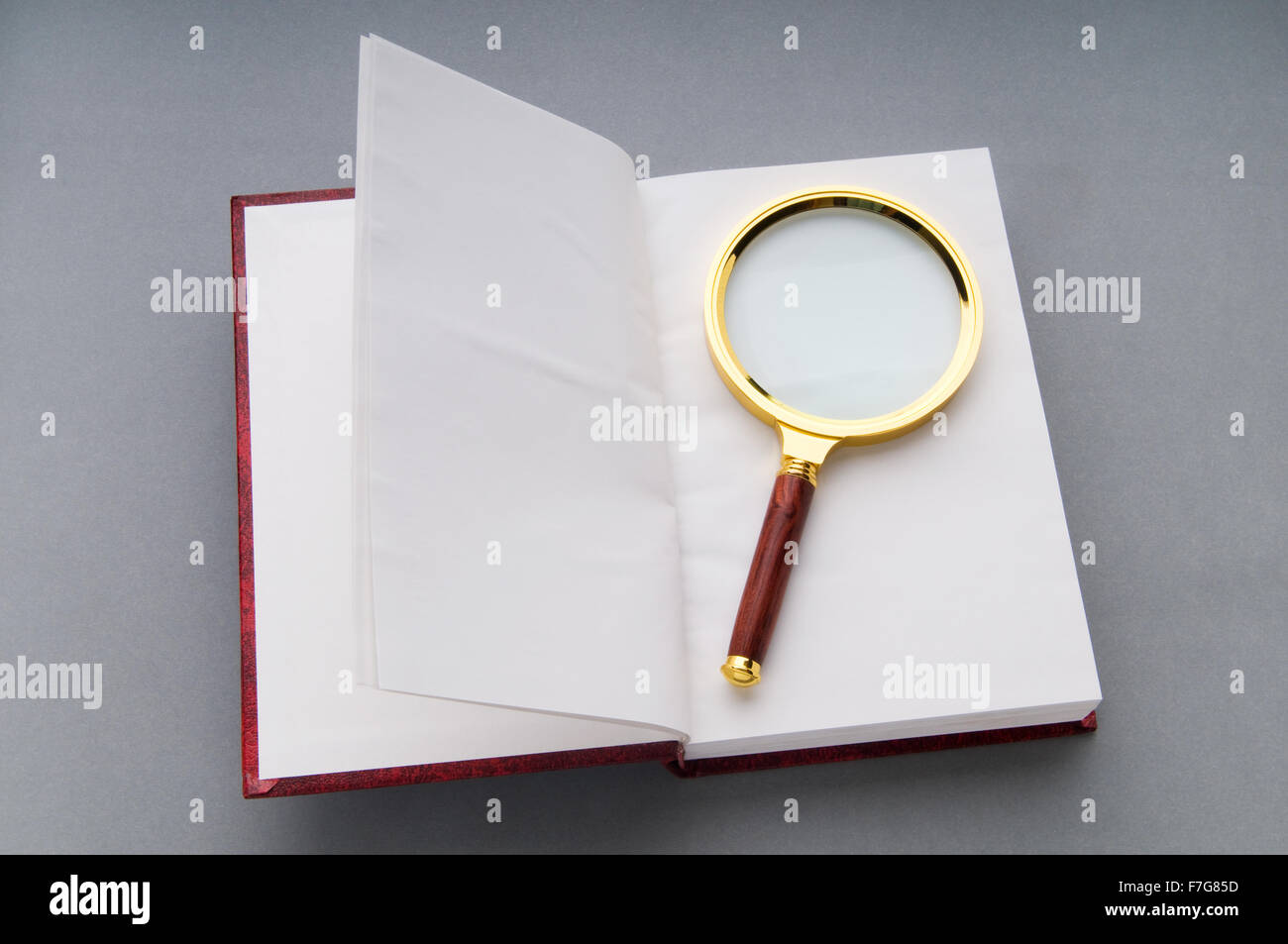 Magnifying glass over the stack of books Stock Photo - Alamy