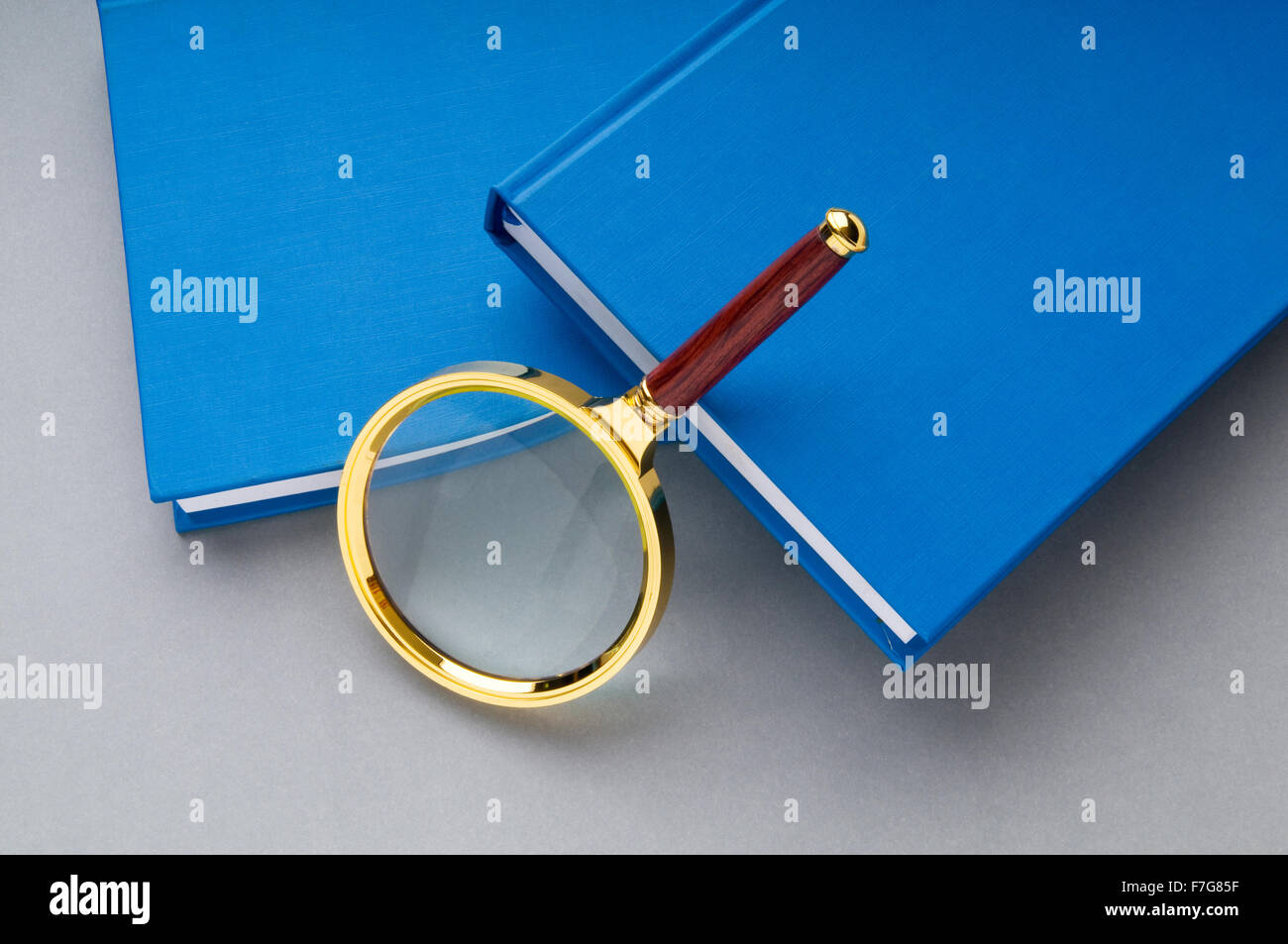 Magnifying glass over the stack of books Stock Photo - Alamy