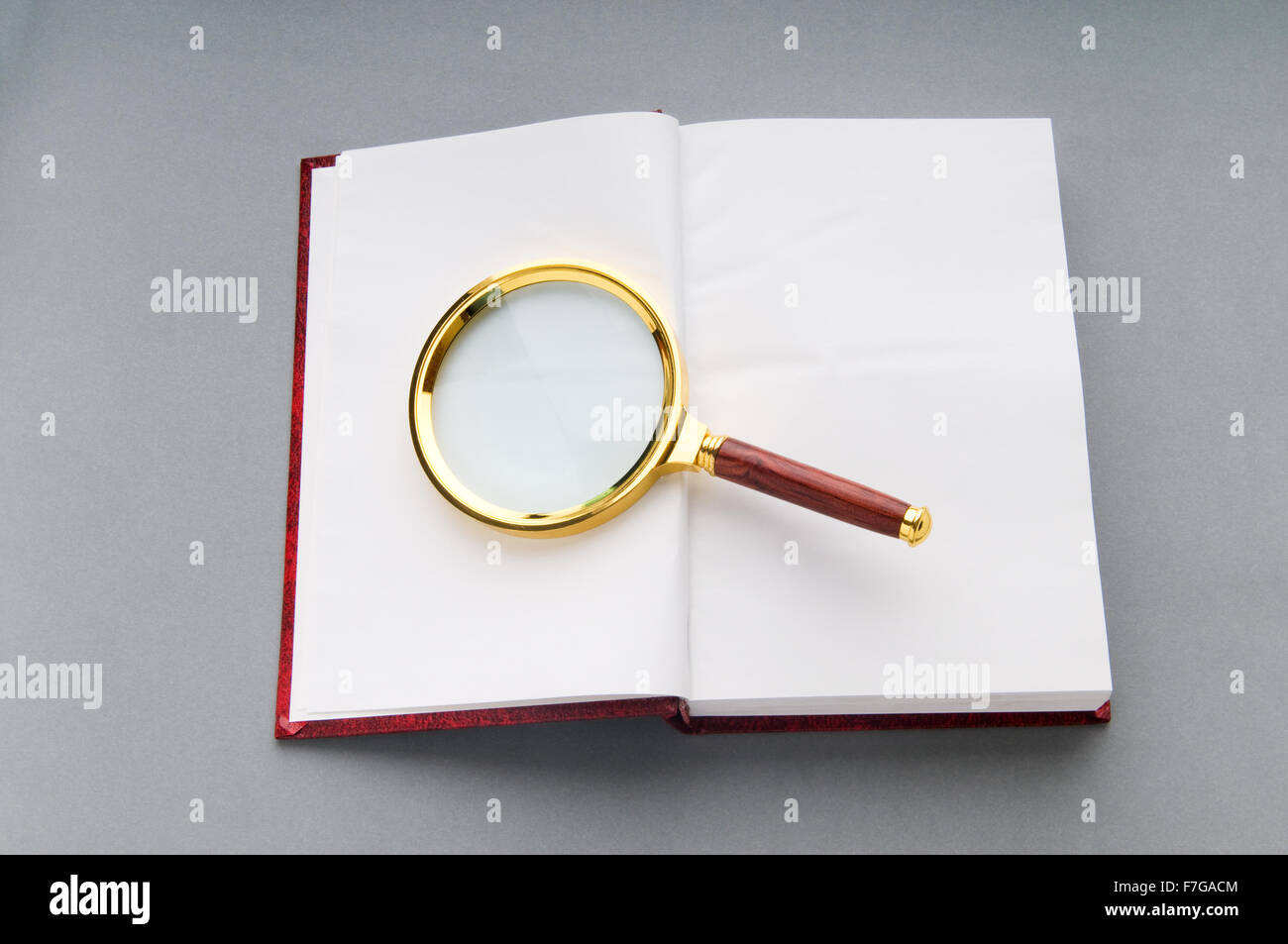 Magnifying glass over the stack of books Stock Photo - Alamy
