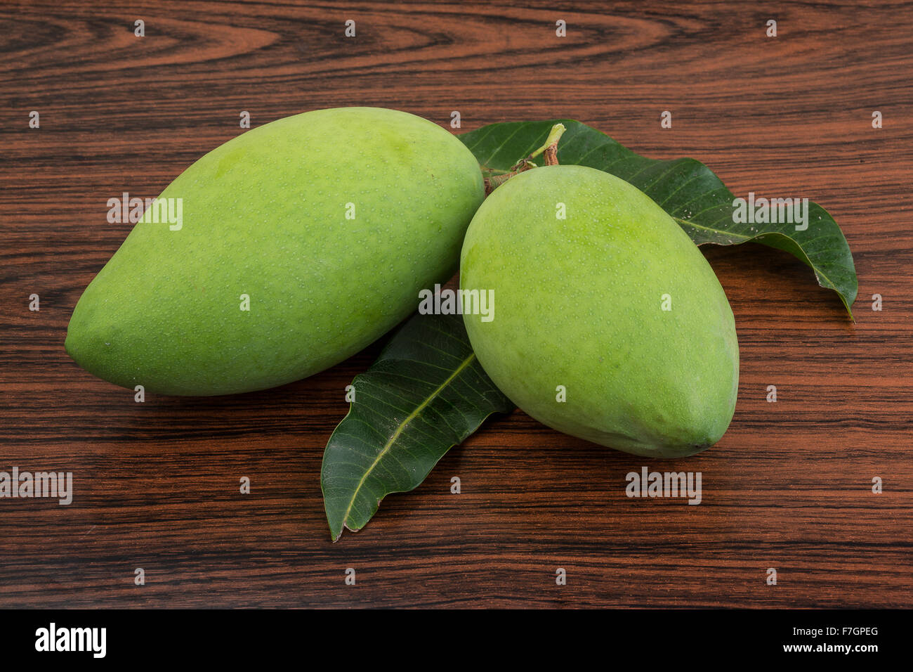 Two Green mango on the wood background Stock Photo - Alamy