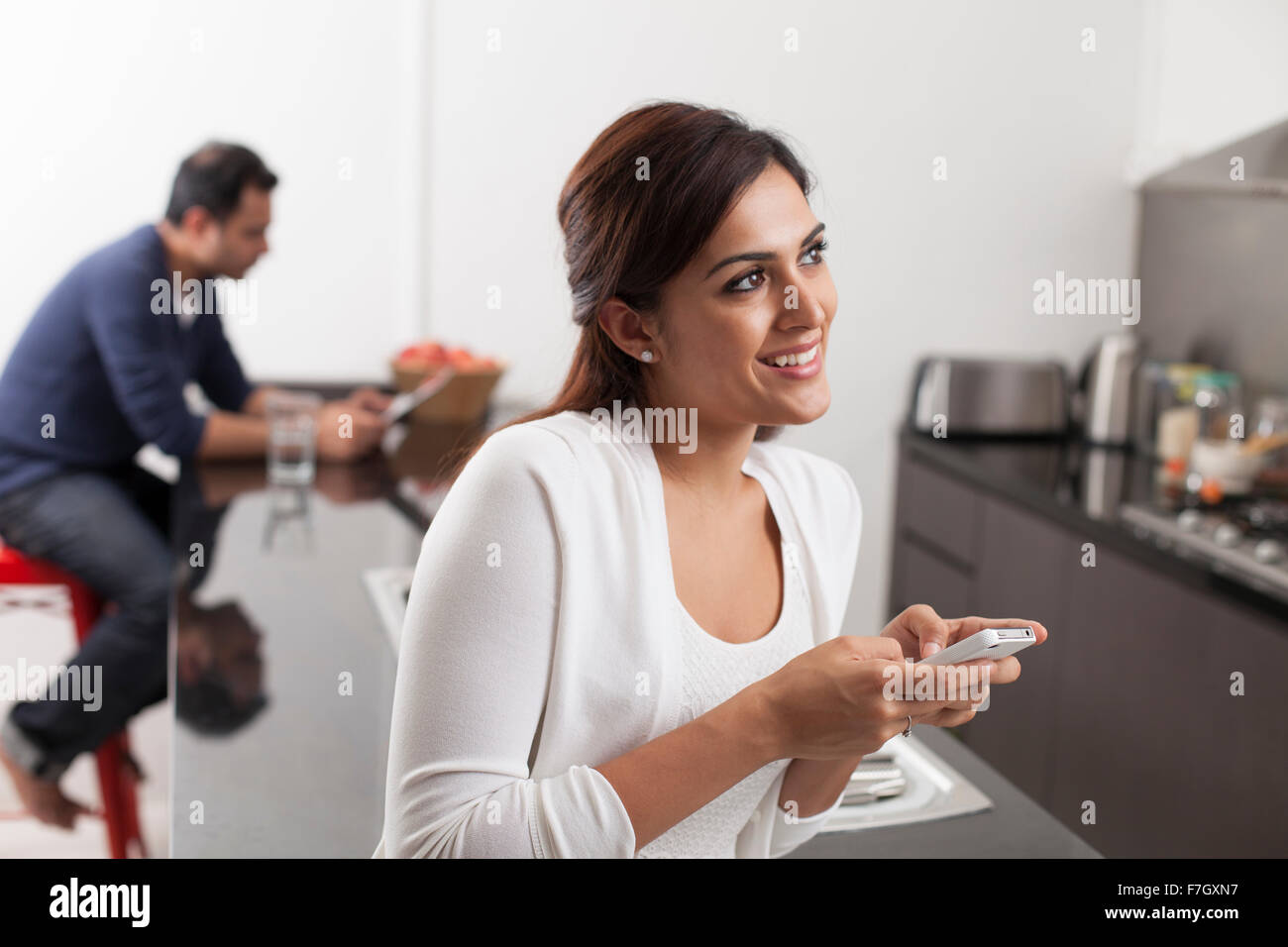 Singapore, Young woman texting in kitchen Stock Photo - Alamy