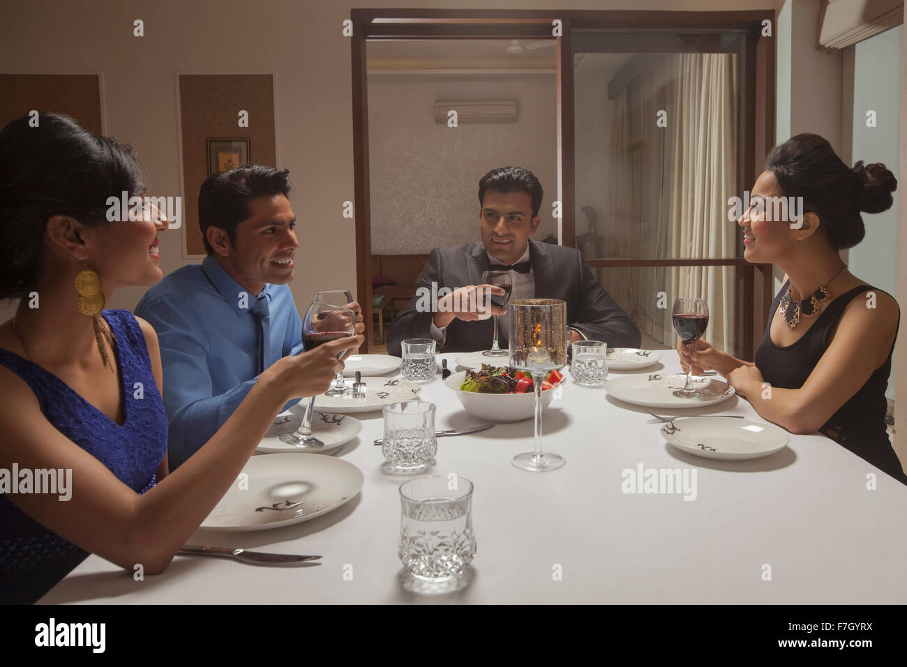India, Friends in formalwear having dinner party Stock Photo - Alamy