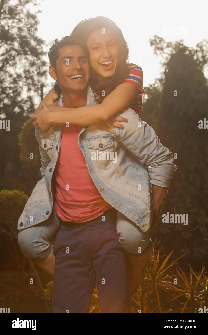 India, Man giving woman piggyback in garden Stock Photo - Alamy