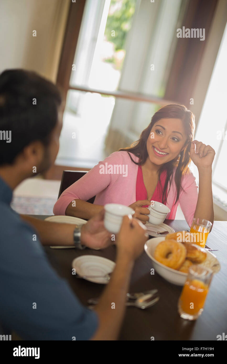 Woman in pink smiling at man at dining table Stock Photo - Alamy