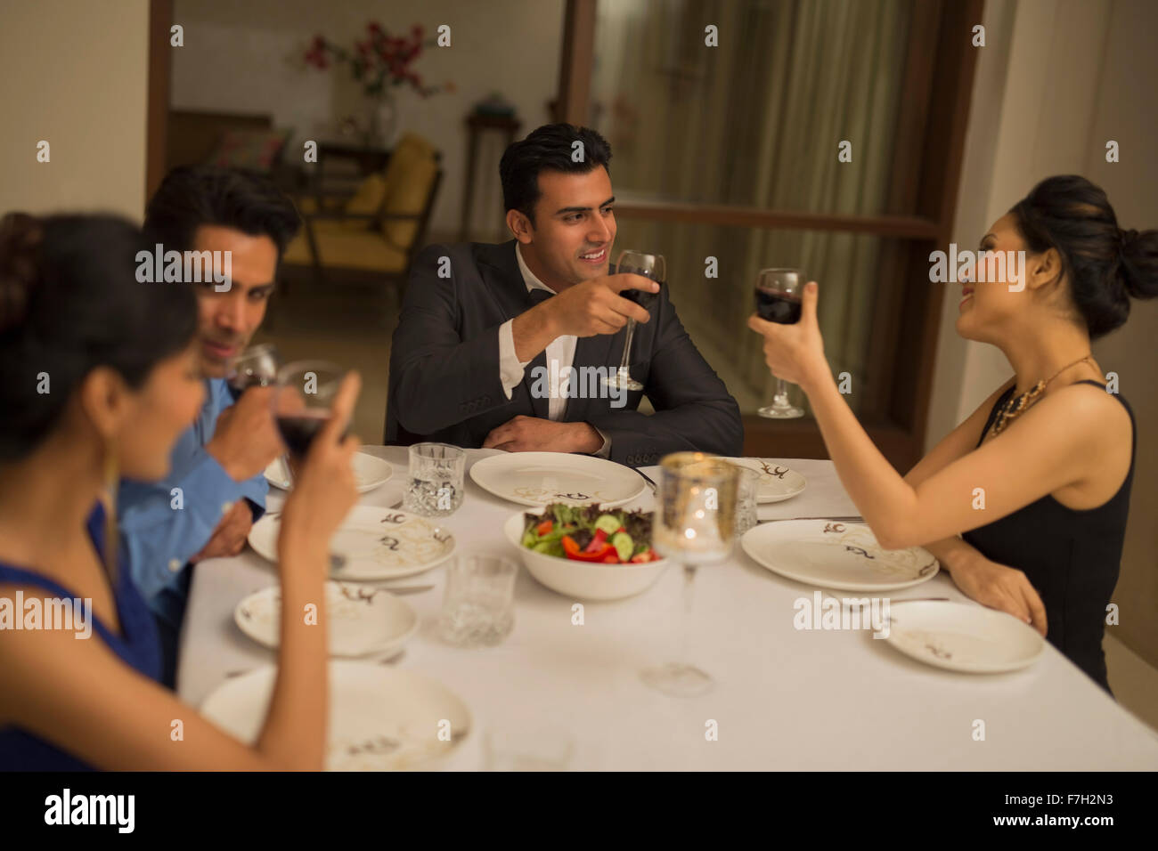 Four friends at formal dining table Stock Photo - Alamy