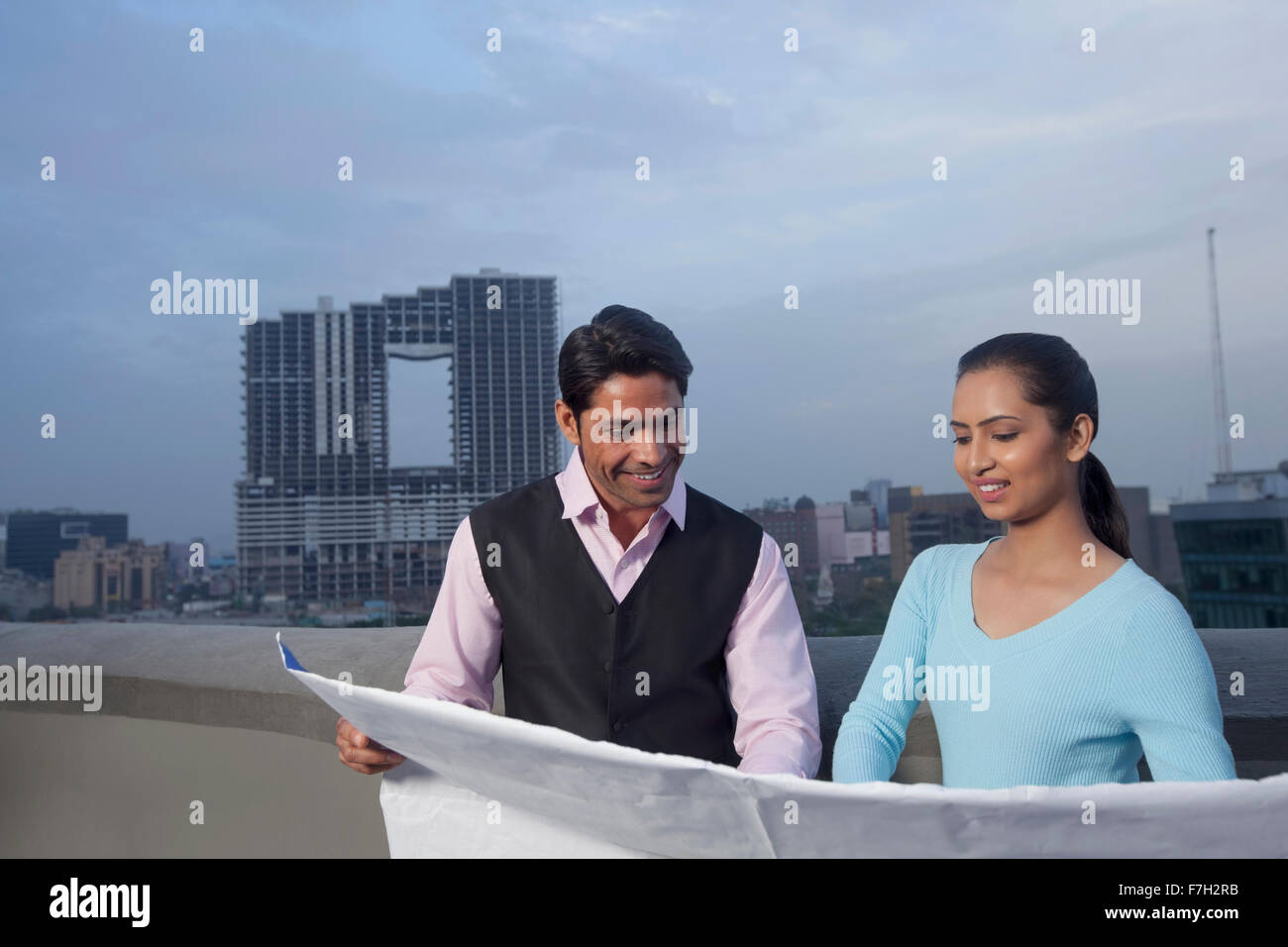 India, Architect and client looking at building plans at construction ...